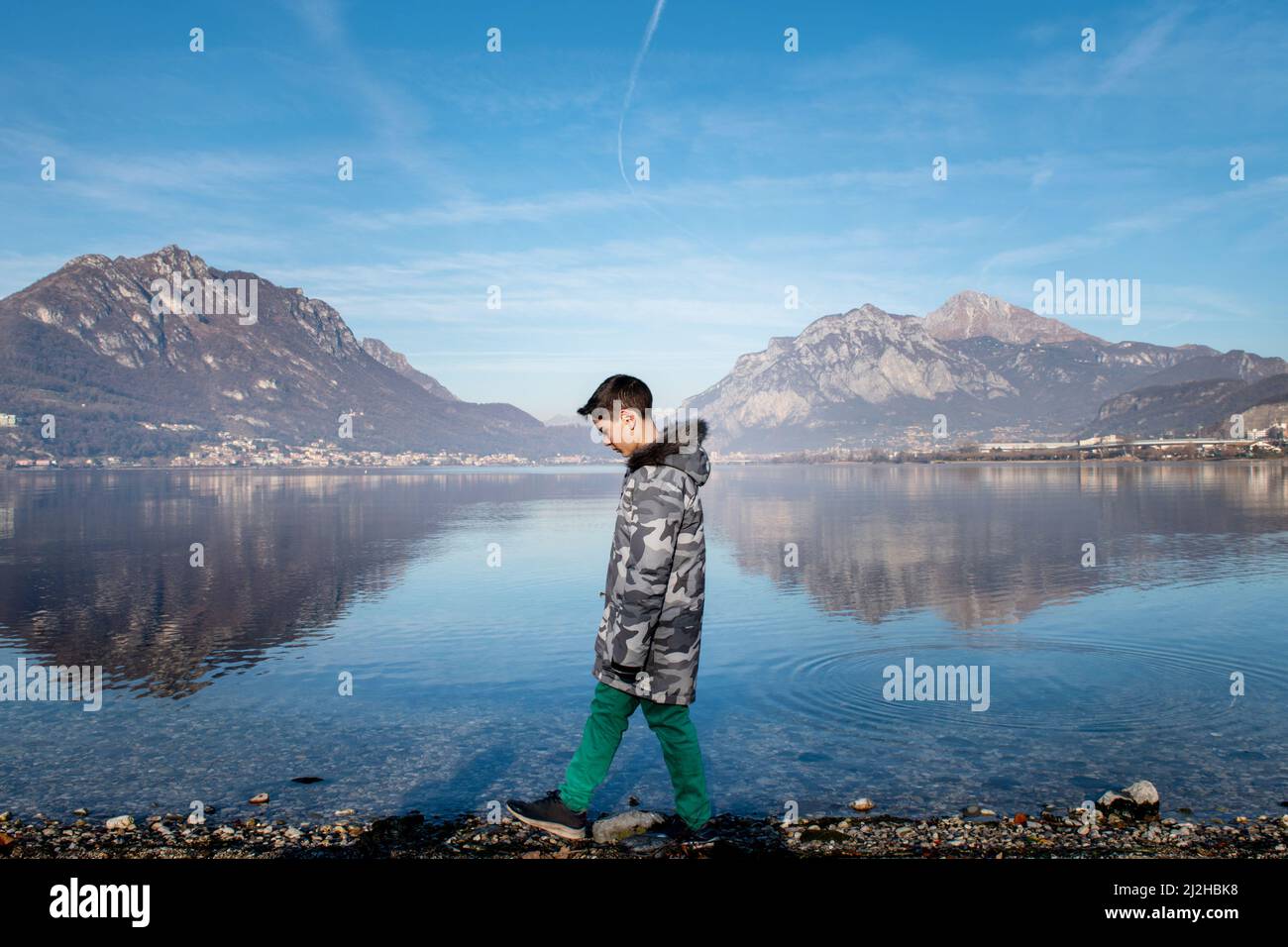 Italy, Boy, walking on lakeshore Stock Photo - Alamy