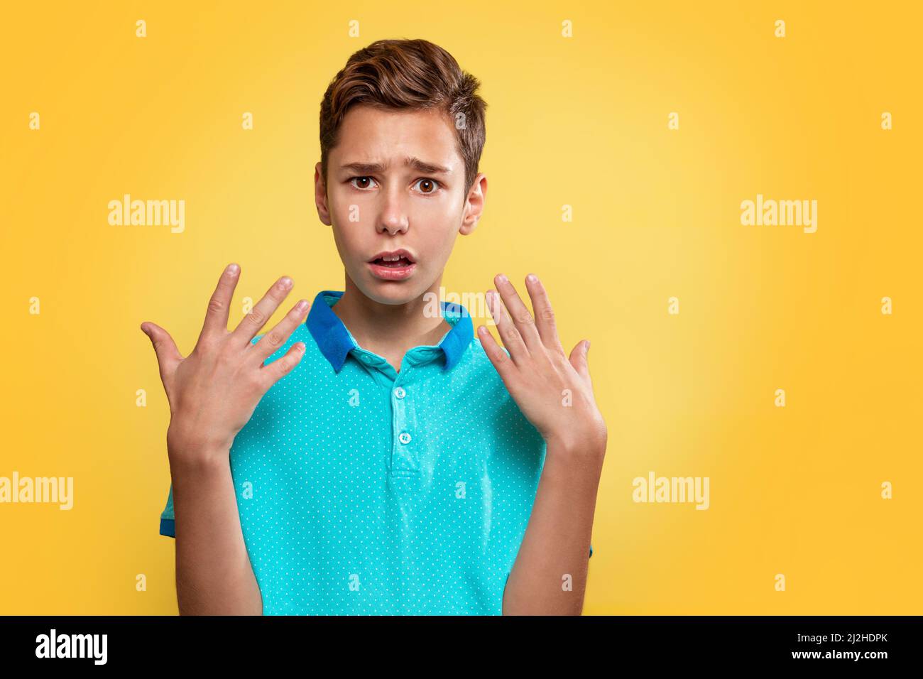 Emotions. A teenage boy in a blue t-shirt waves his arms in surprise ...