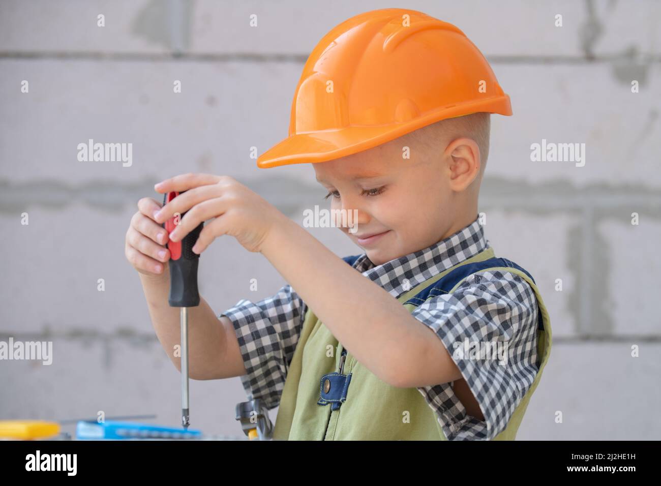 Child play with supplies, tools saw, hammer, screwdriver, helmet ...
