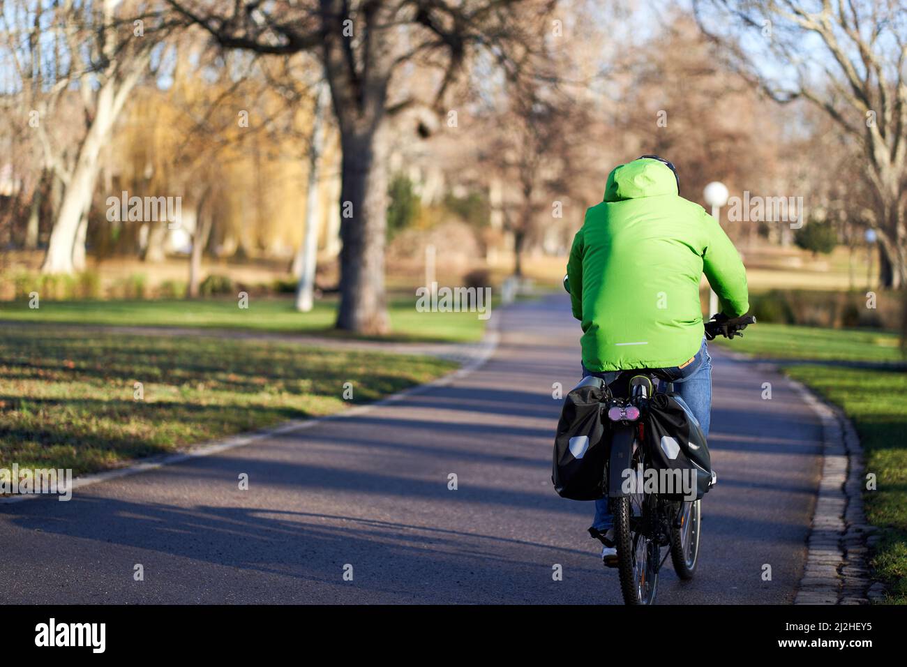 Man riding bike in the park. Person with green jacket is moving on his ...