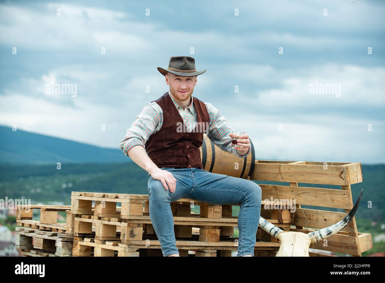 Cowboy farmer man drinks a whiskey in country side wearing western ...