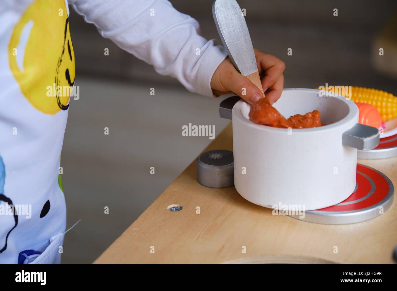 detail of a hand of a little girl cooking in the toy kitchen at home ...