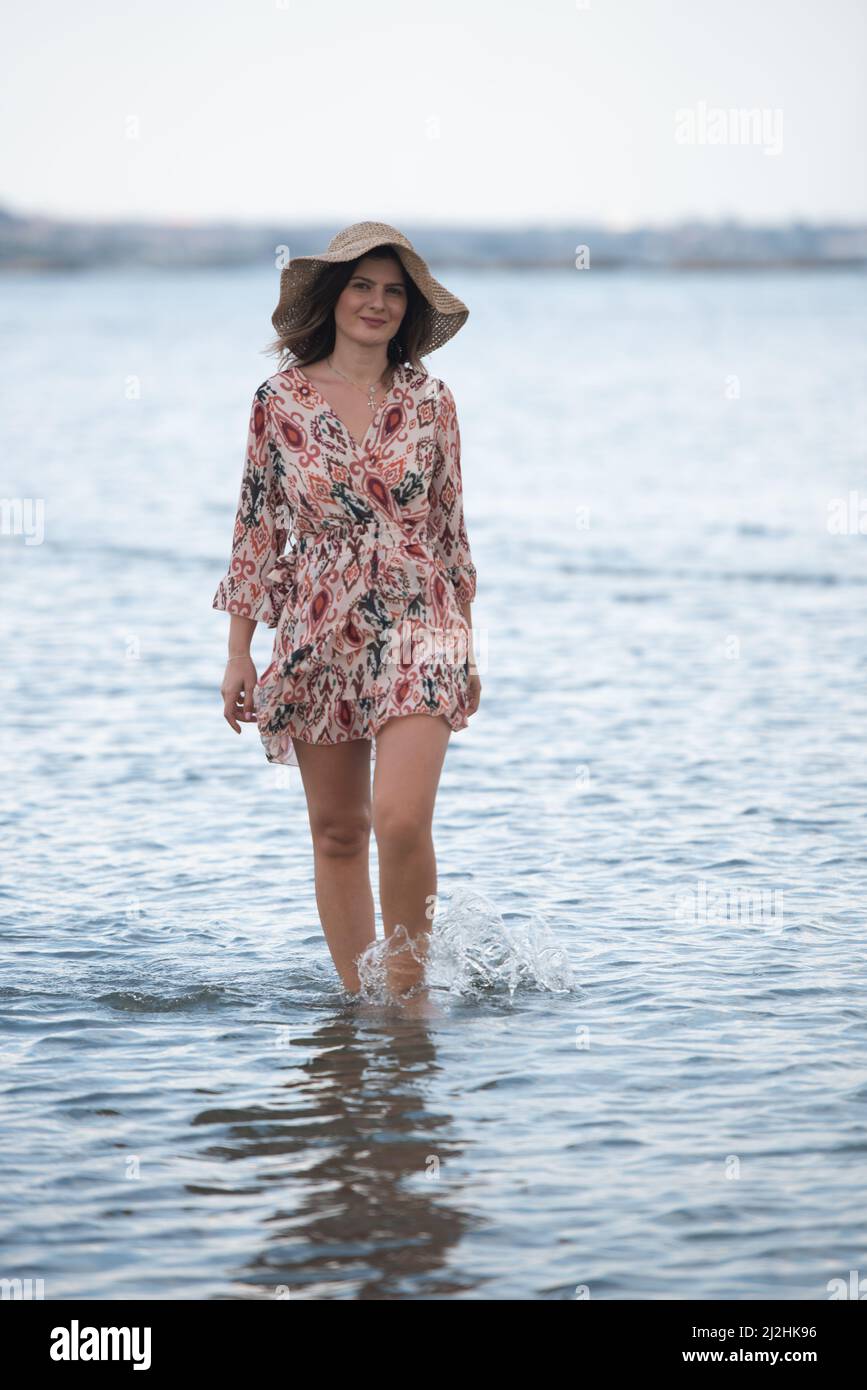 Attractive woman wearing hat walking in the sea. Summer vacation Cyprus ...