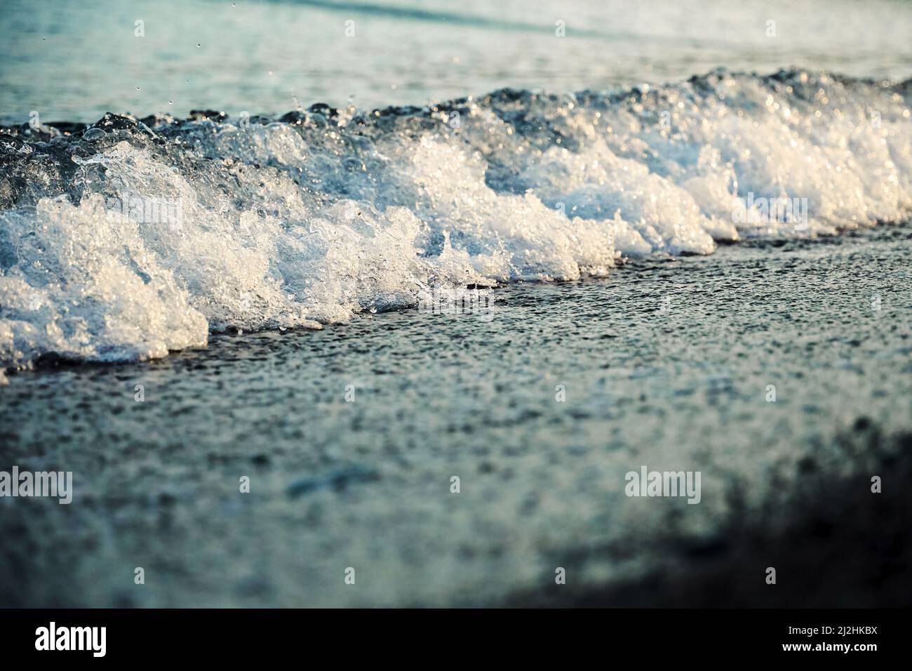 Sea wave wave in the rays of the daytime sun comes on the shore with ...