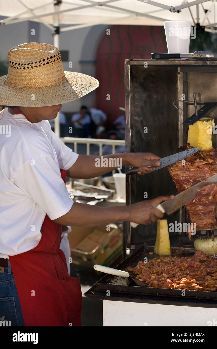 A food vendor carving delicious grilled meat on a spit for Cinco de ...