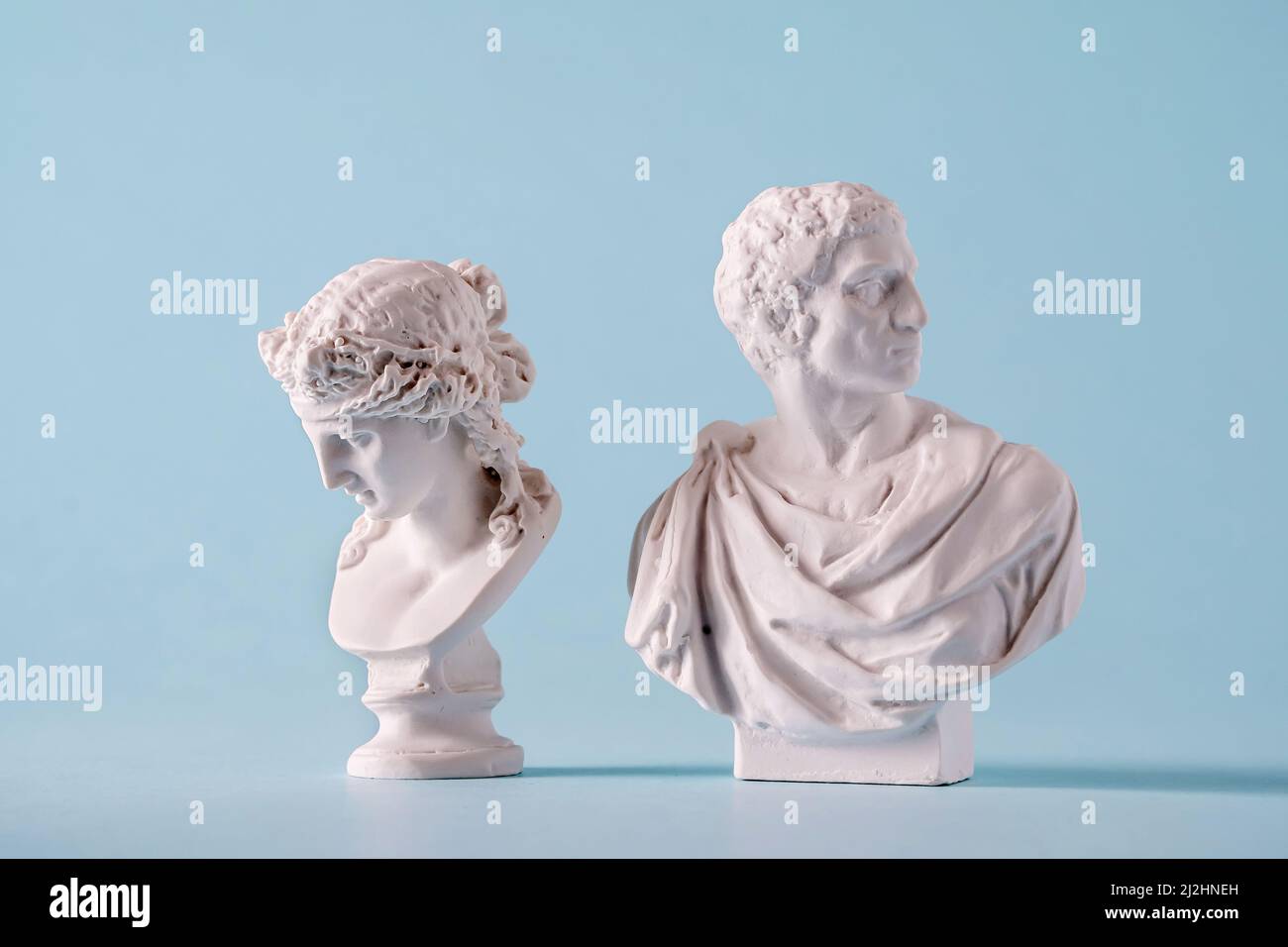 Two white Roman or Grecian antique style busts of young men over a blue ...