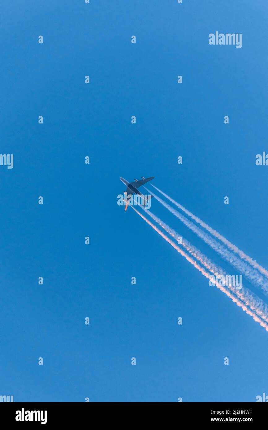 Airplane in a blue cloudless sky with colored colorful contrails ...