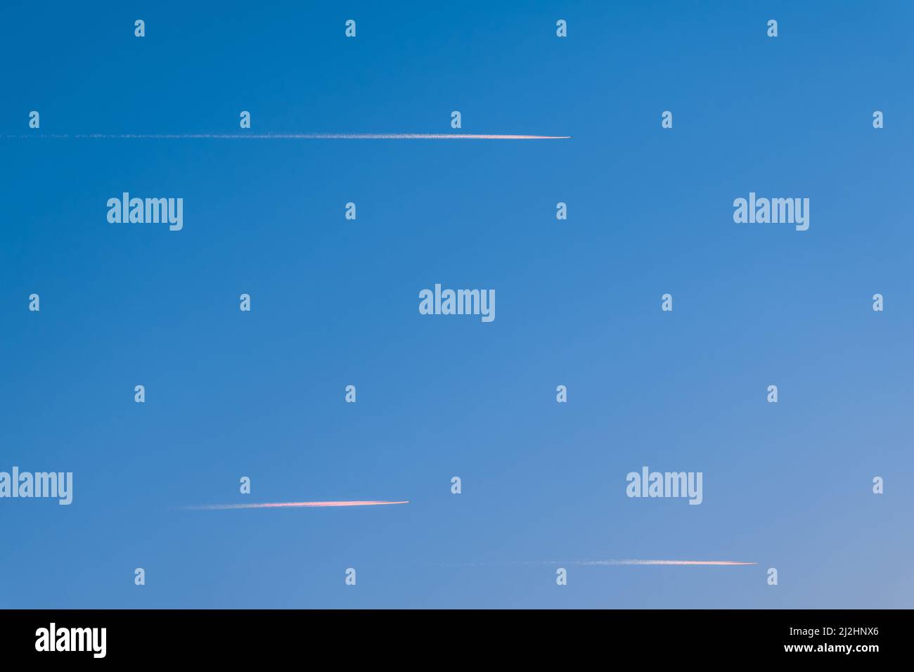Airplane in a blue cloudless sky with colored colorful contrails ...