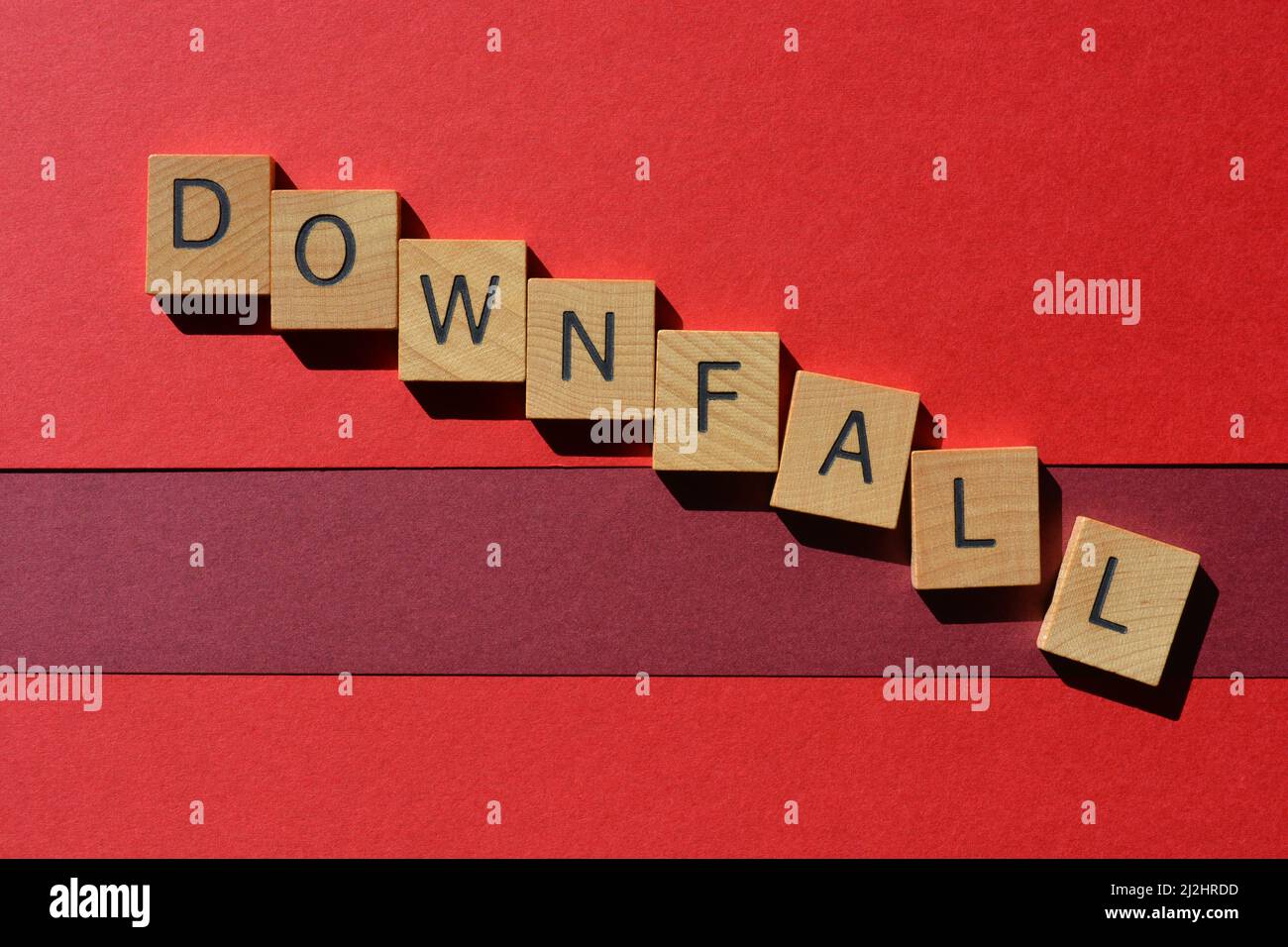 Downfall, word in wooden alphabet letters isolated on red background ...