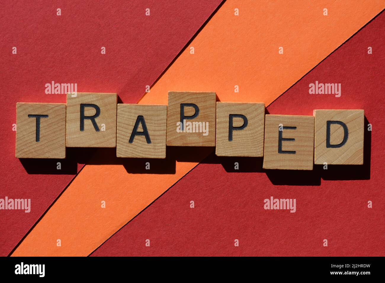 Trapped Word In Wooden Alphabet Letters Isolated On Red Background trapped-word-in-wooden-alphabet-letters-isolated-on-red-background