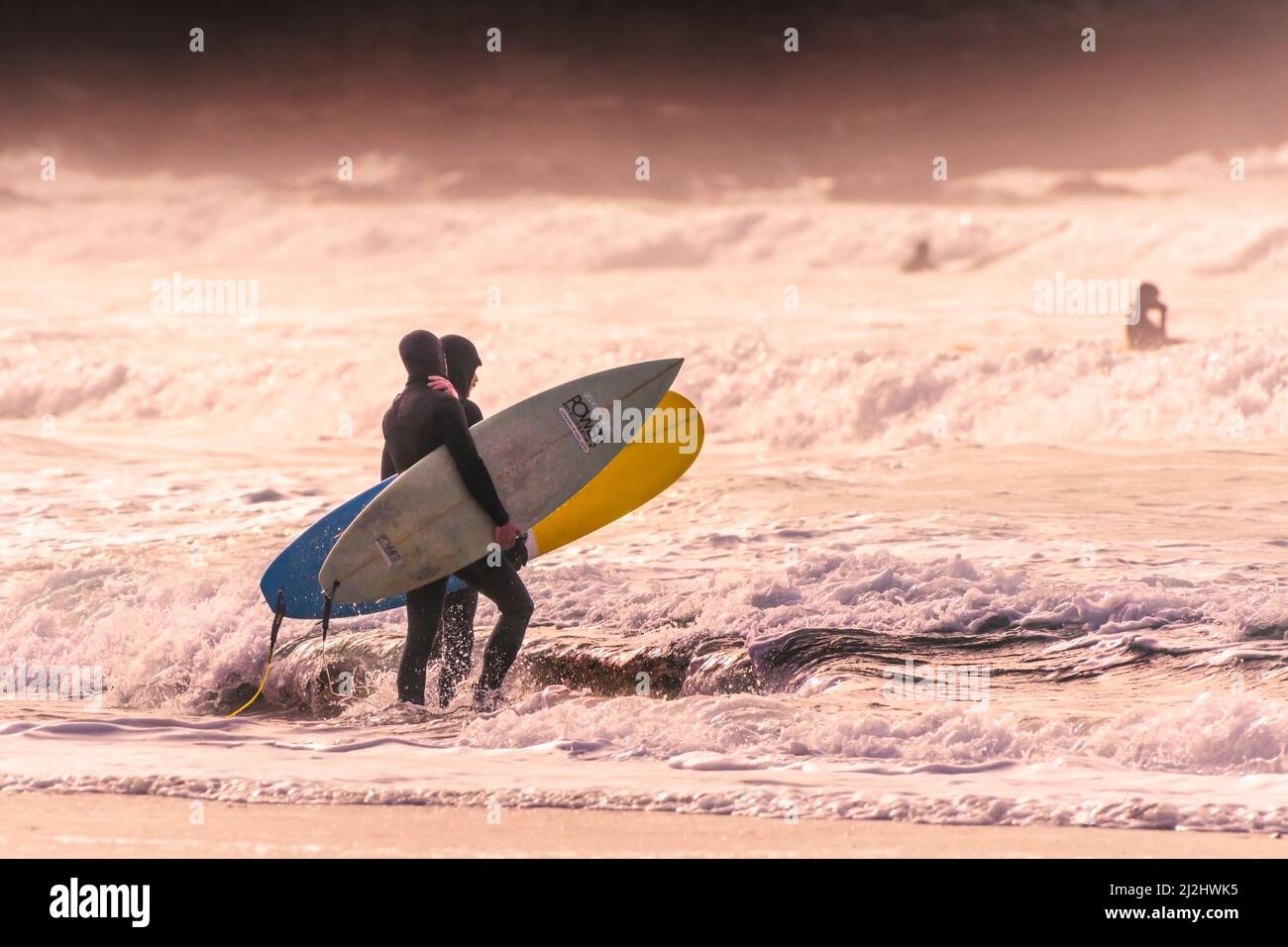 Surfers carrying their surfboards at the start of their surfing session ...
