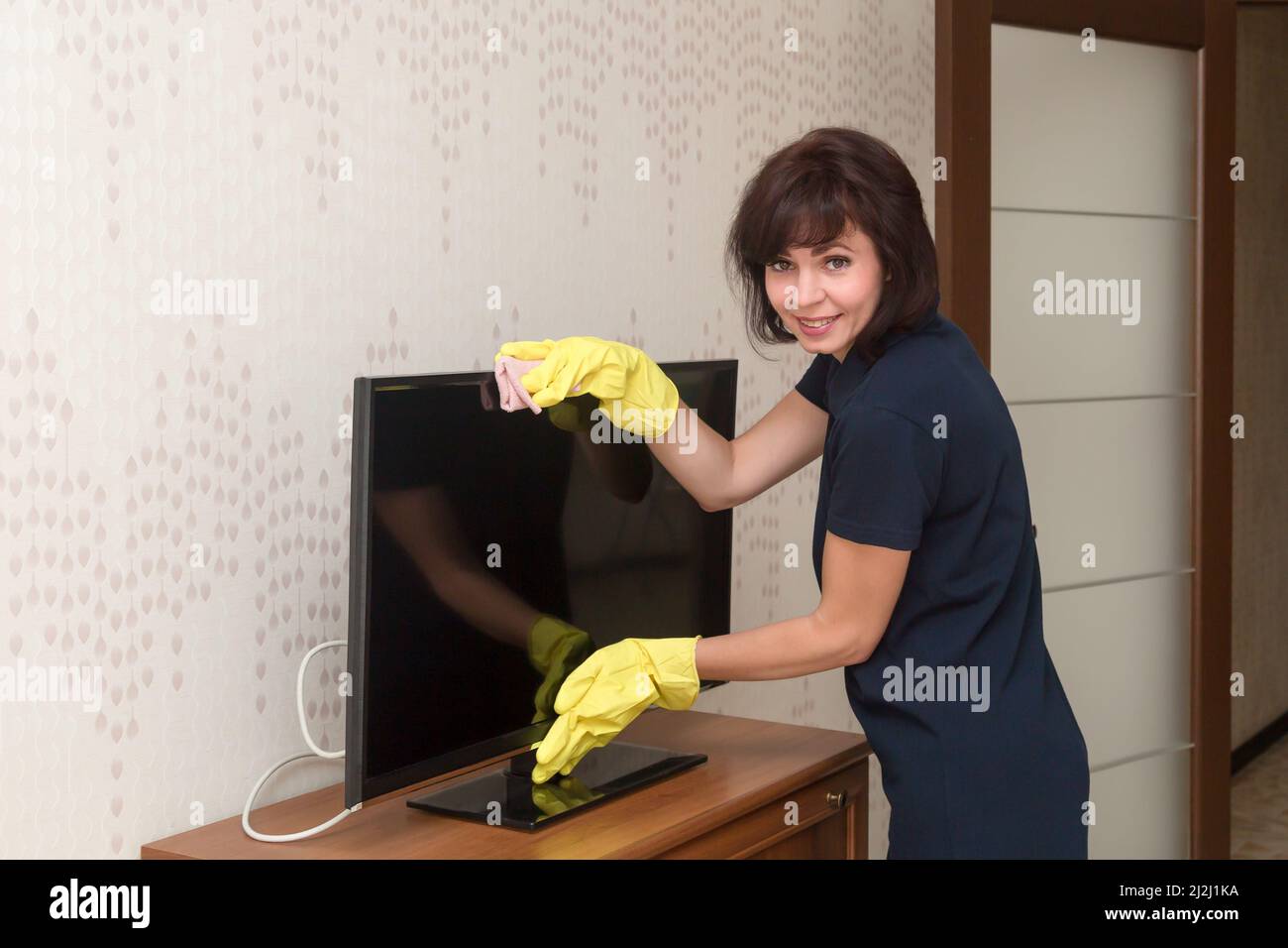 Wife dusting TV screen while cleaning house Stock Photo - Alamy