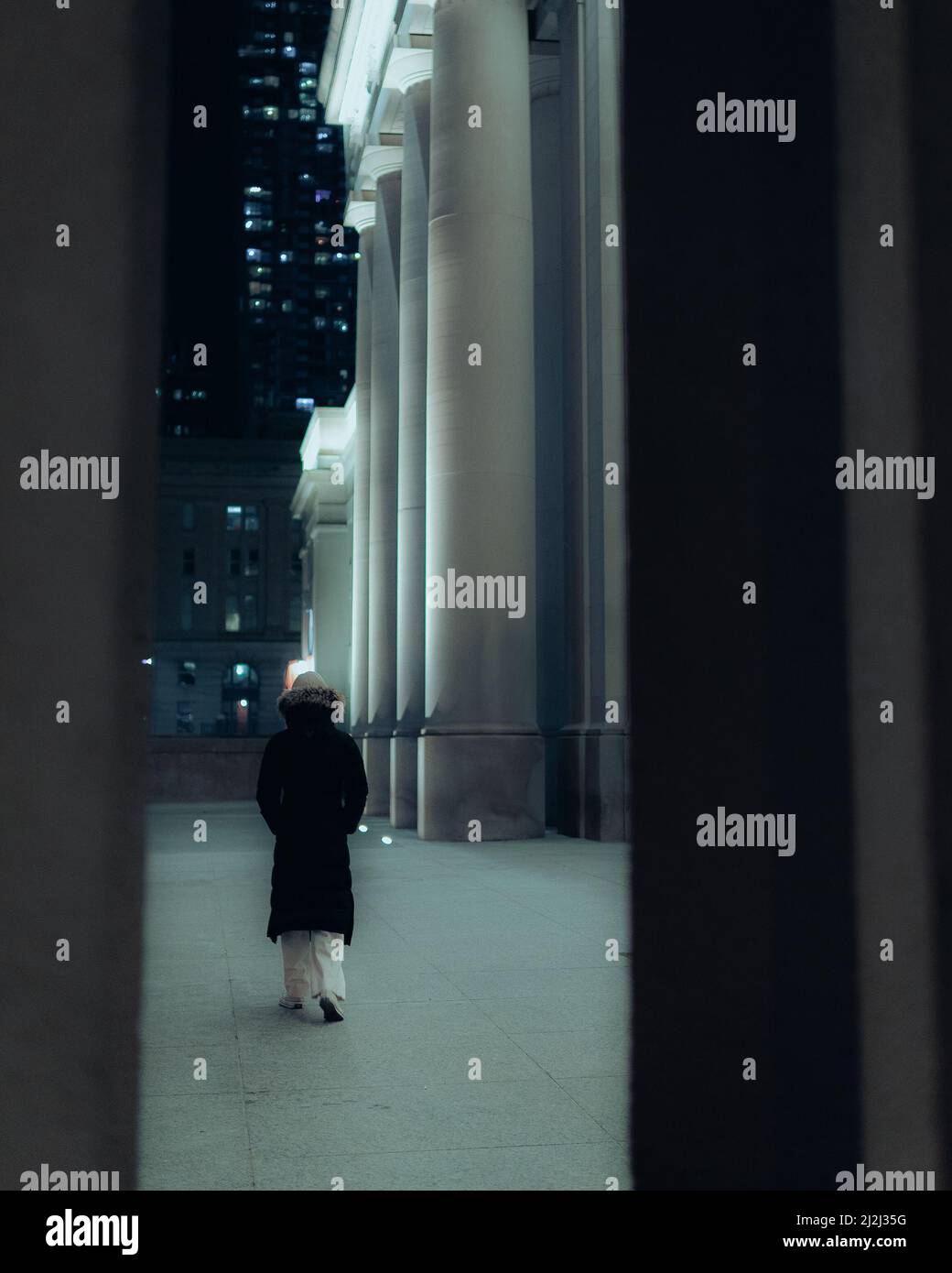 A vertical shot of a person walking through columns in Toronto, Canada ...