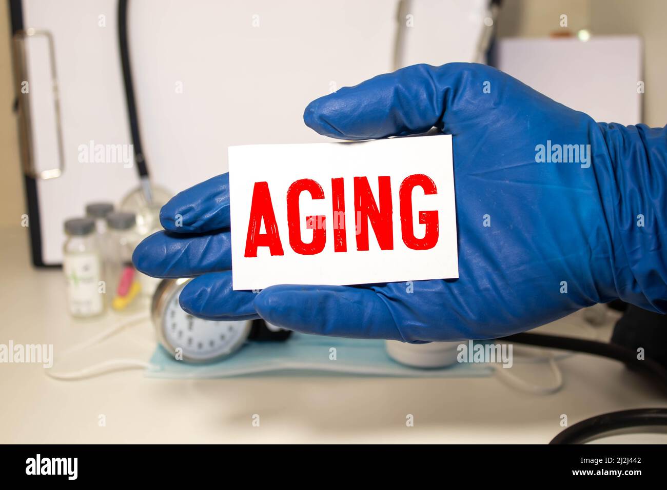 Aging is a word written on white paper on a blue background with pills ...