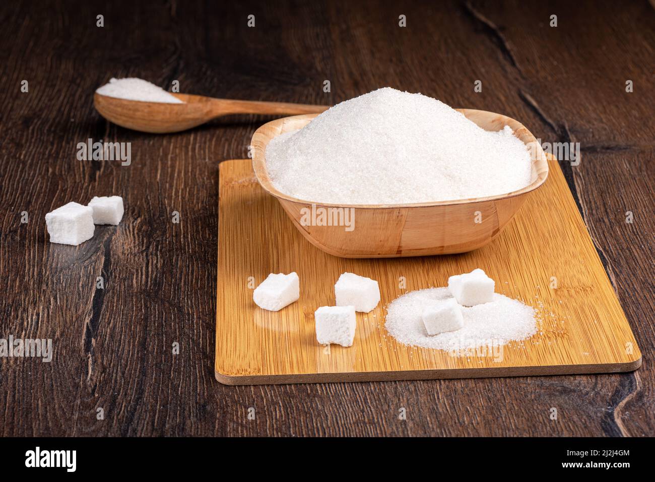 White granulated sugar and lump sugar on a cutting board. Sweet ...