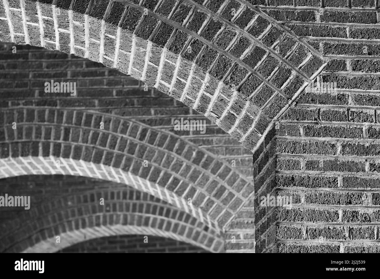 Arcade of vintage brick arches outside on the ground level in black and ...