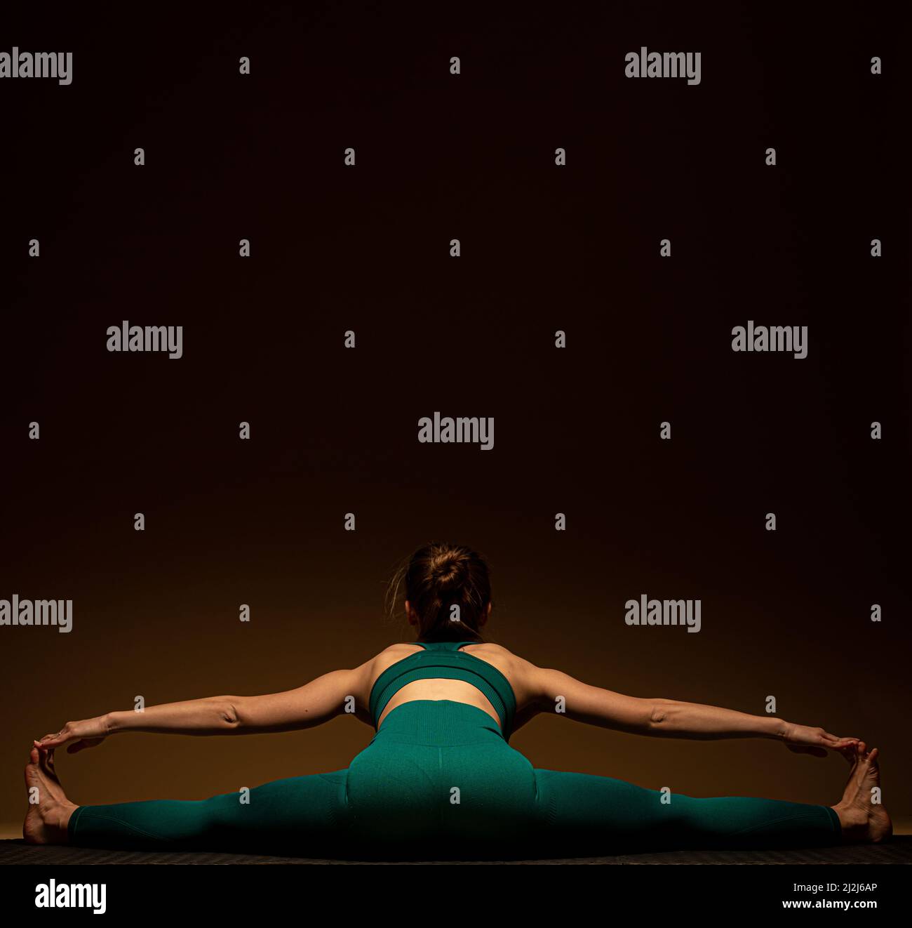 Attractive and beautiful young girl is doing some splits on the ground ...