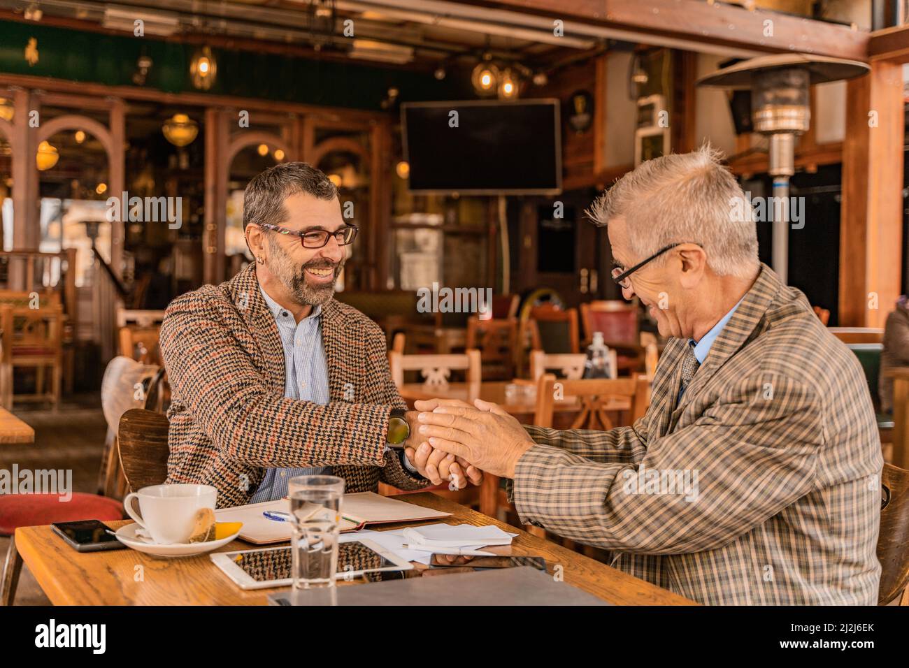Two senior and handsome businessmen are making a deal and smiling Stock ...