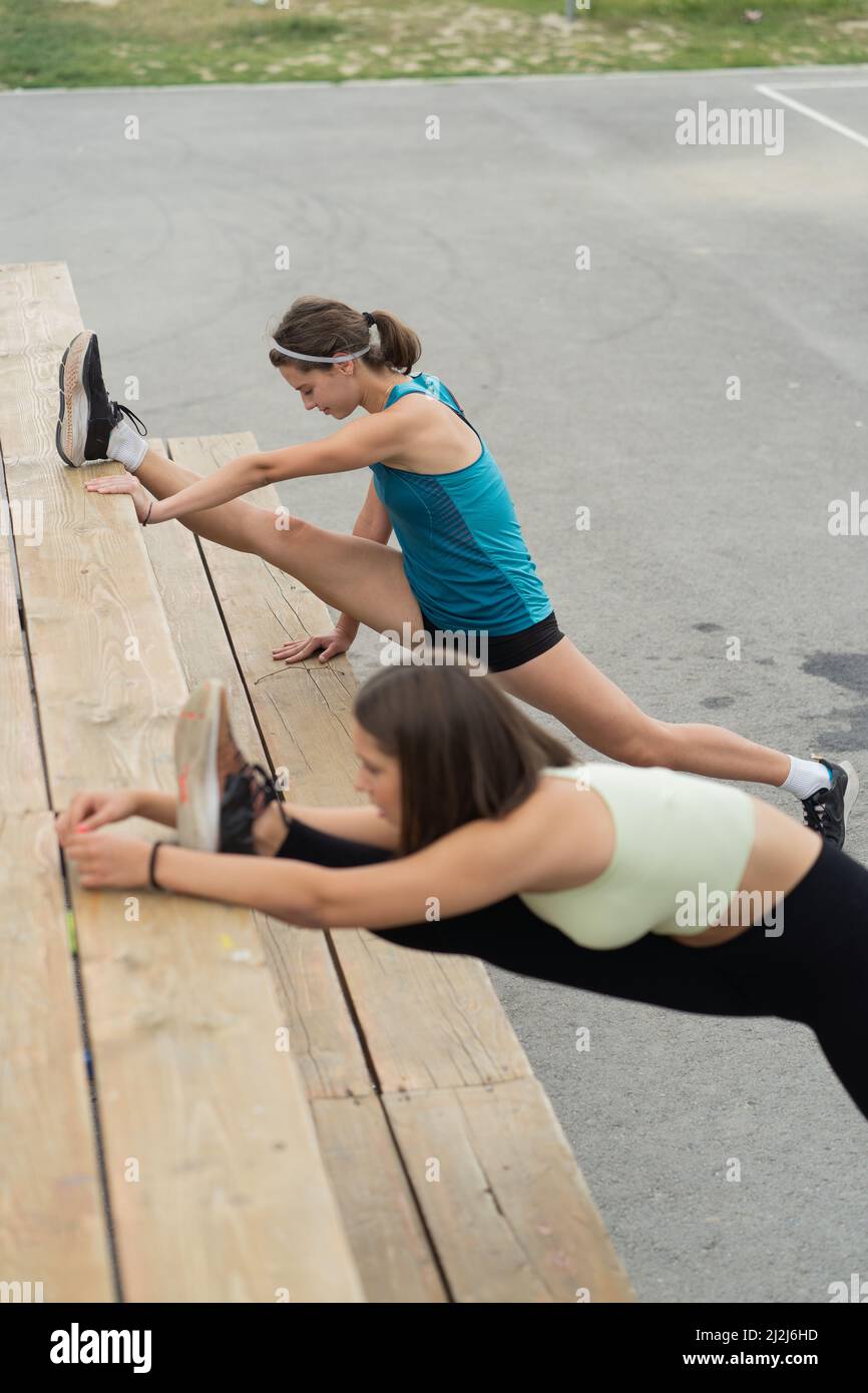 Both attractive and beautiful girls are stretching while one of them is ...