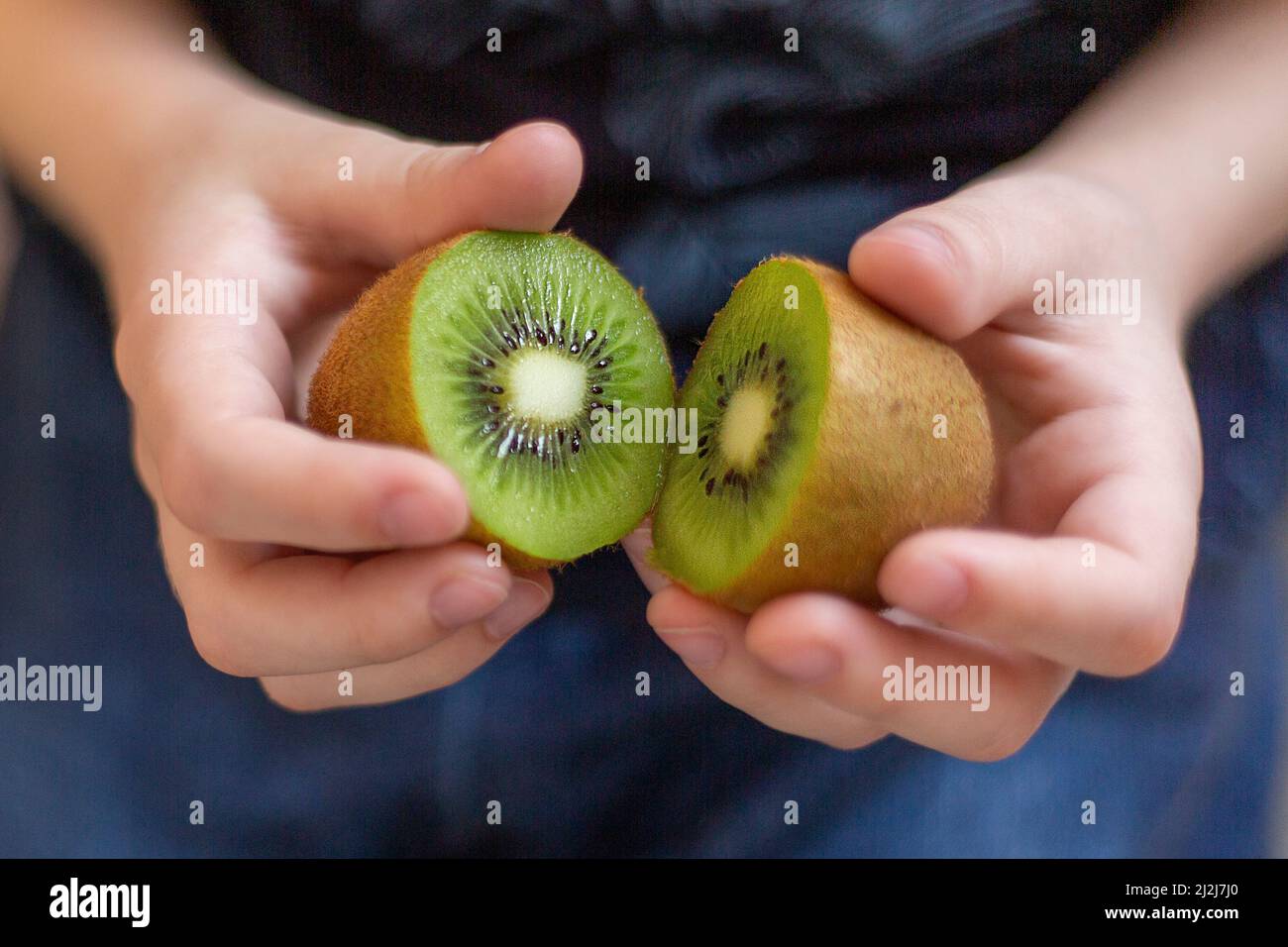 Kiwi opens in the hands of a child and shows a beautiful pattern of ...