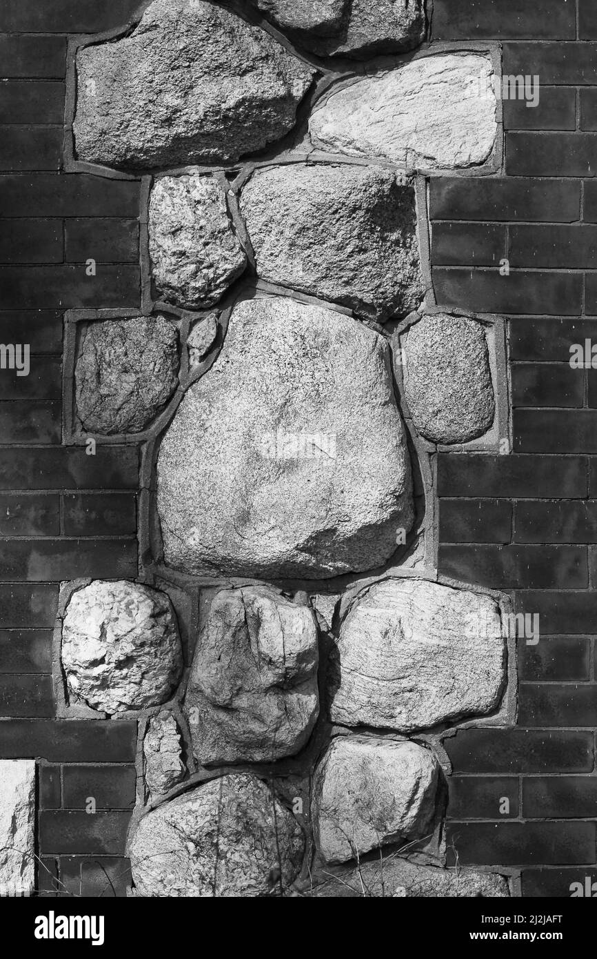 Rustic stone wall built with round boulders and granite stones in black ...
