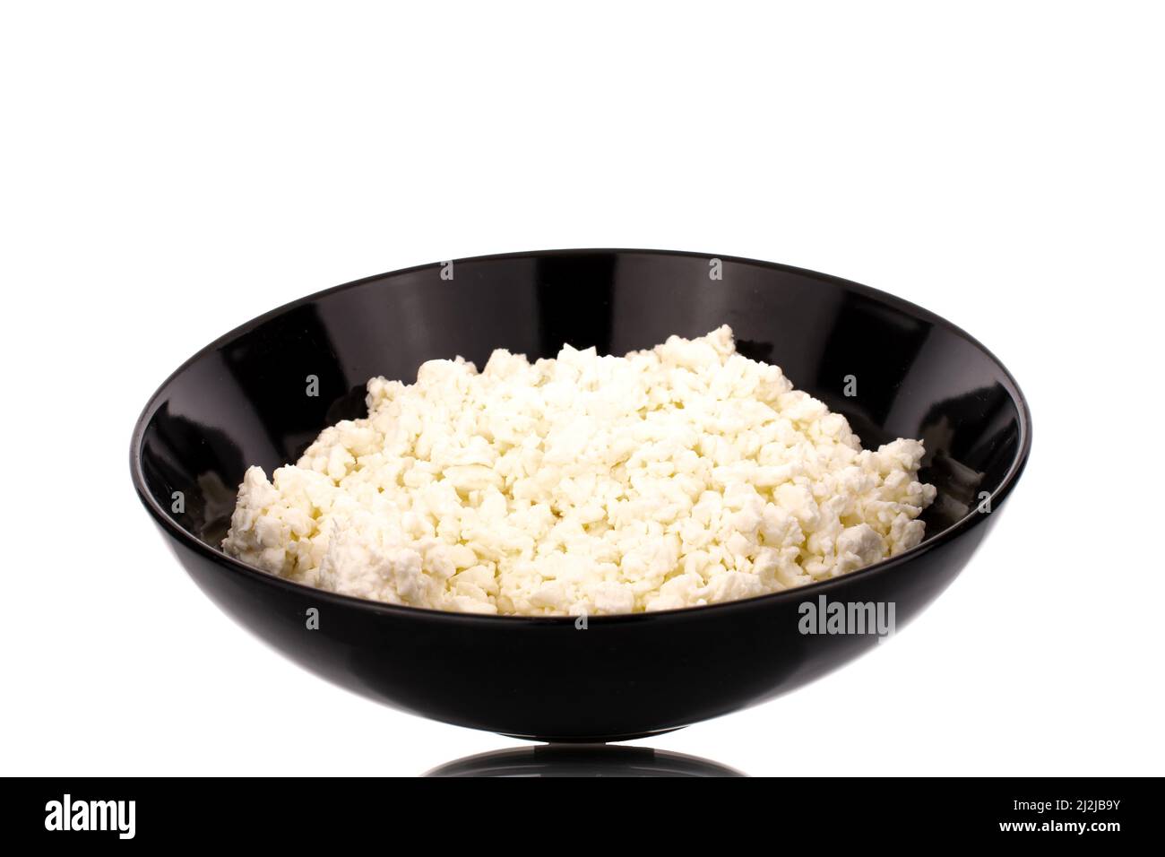 Fragrant tasty cottage cheese in a black ceramic plate, macro, isolated ...