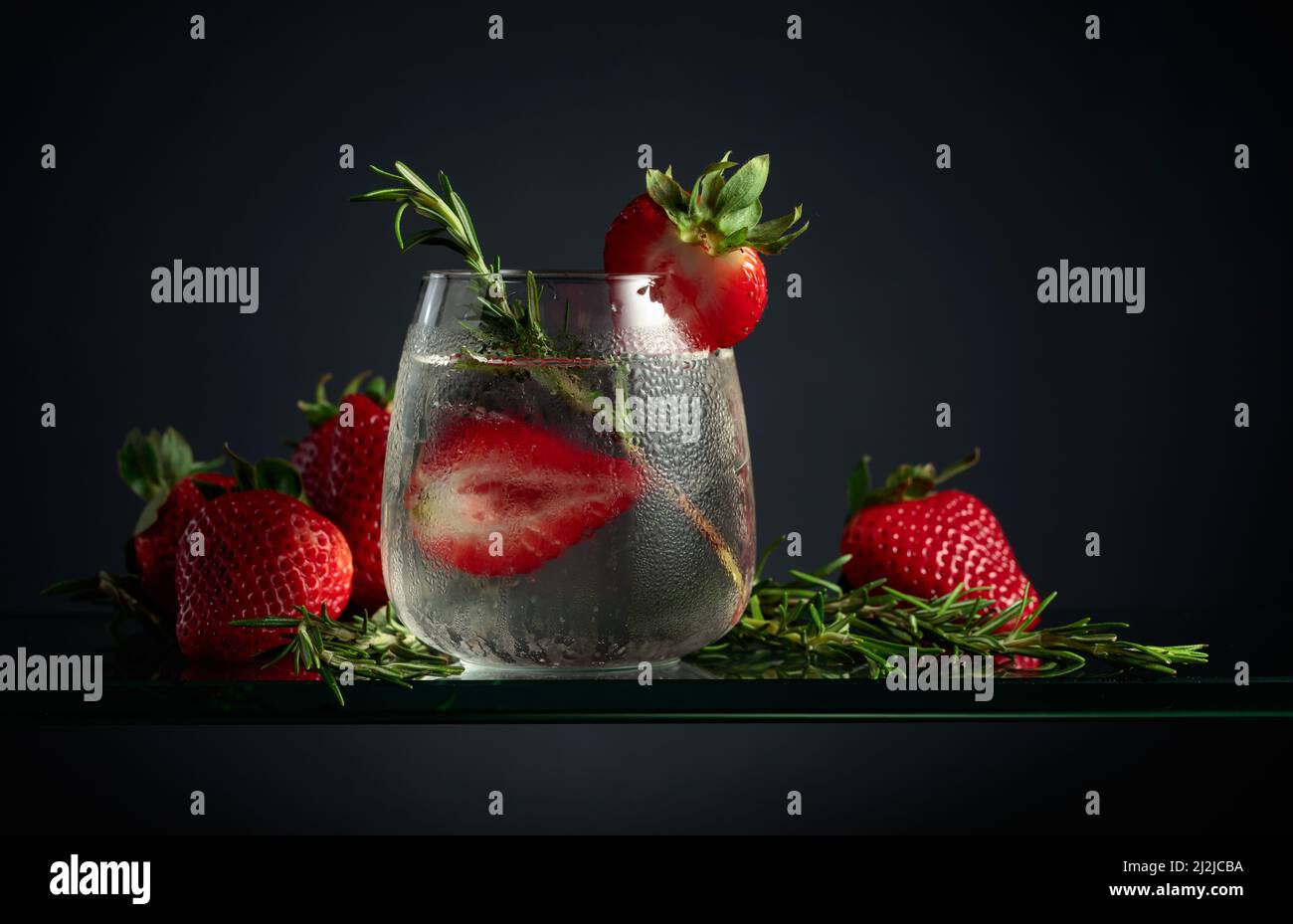 Cocktail gin tonic with ice, strawberries, and rosemary in a frozen ...