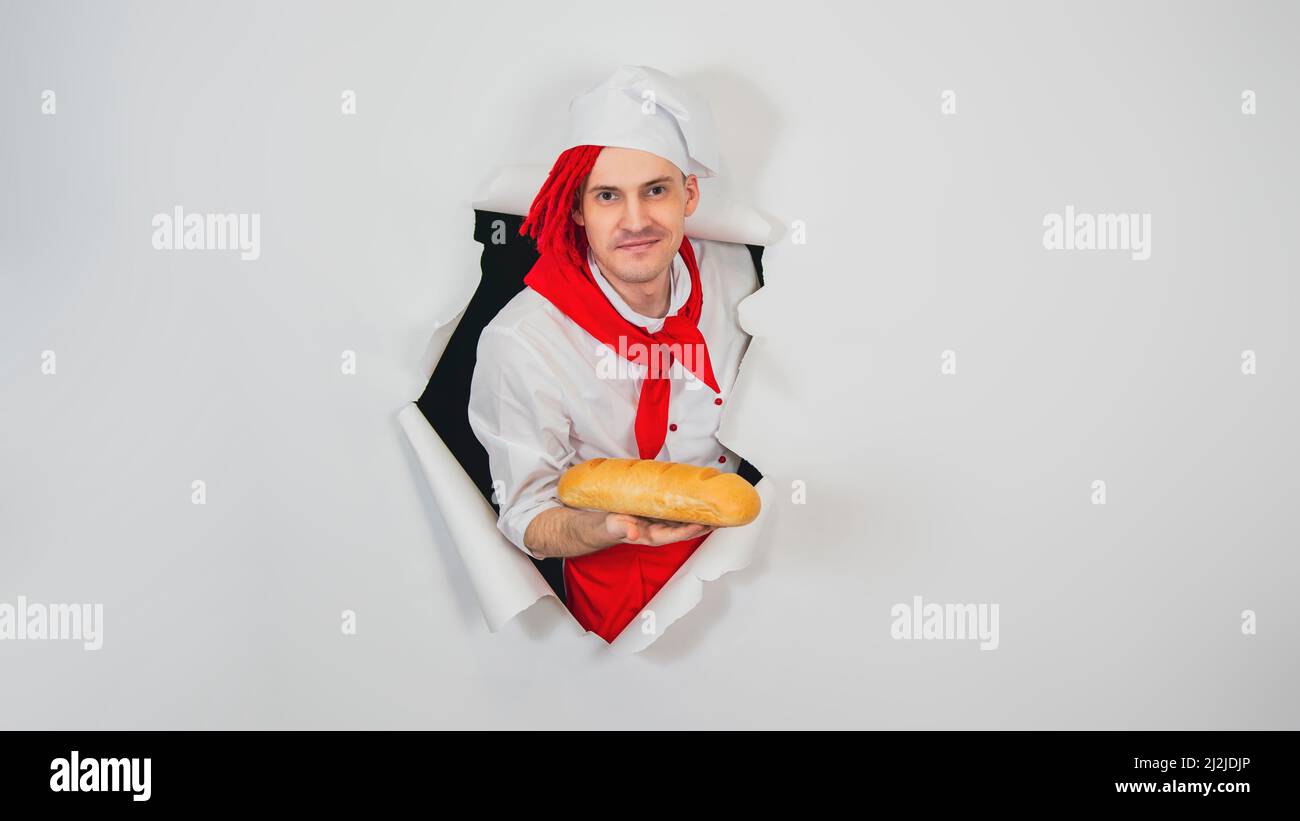 Young man with red dreadlocks dressed as chef holding white bread. Male ...