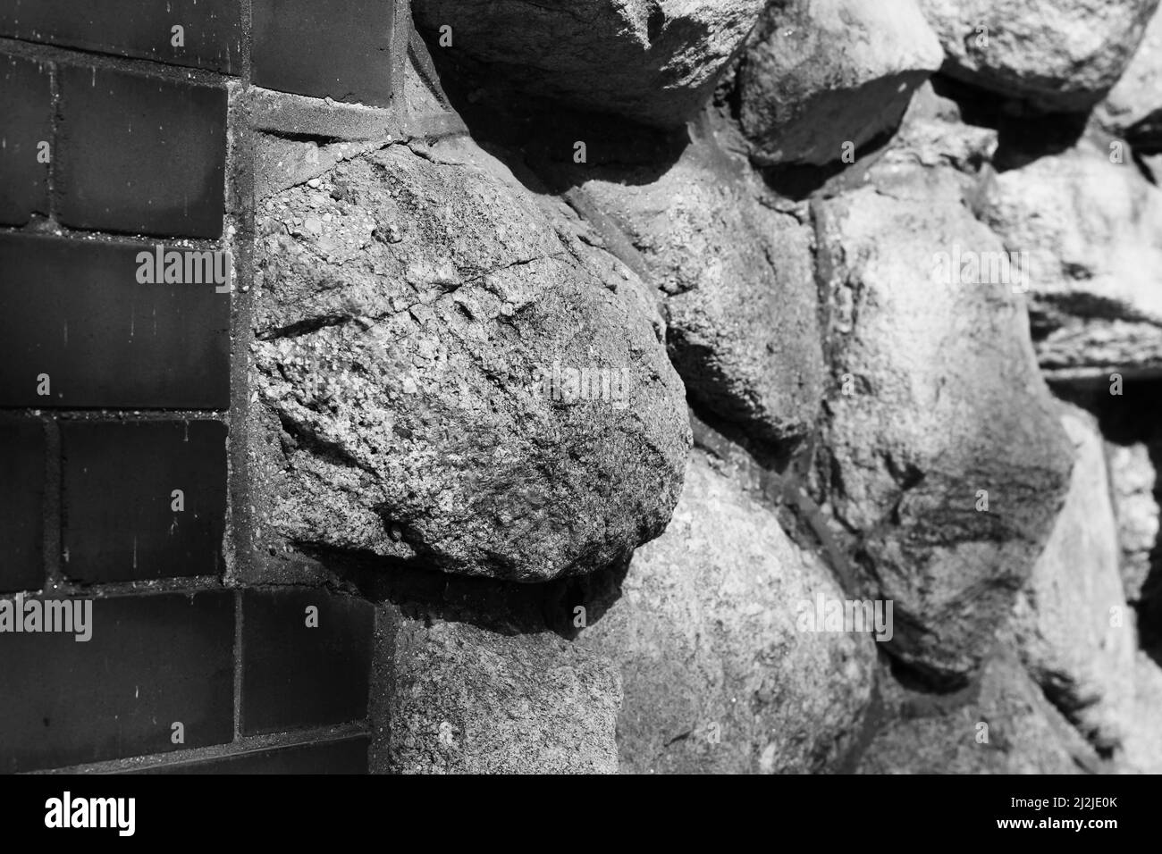 Rustic stone wall built with round boulders and granite stones in black ...