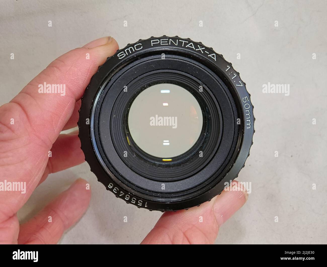 Fingers holding an old Pentax prime camera lens (front view Stock Photo ...