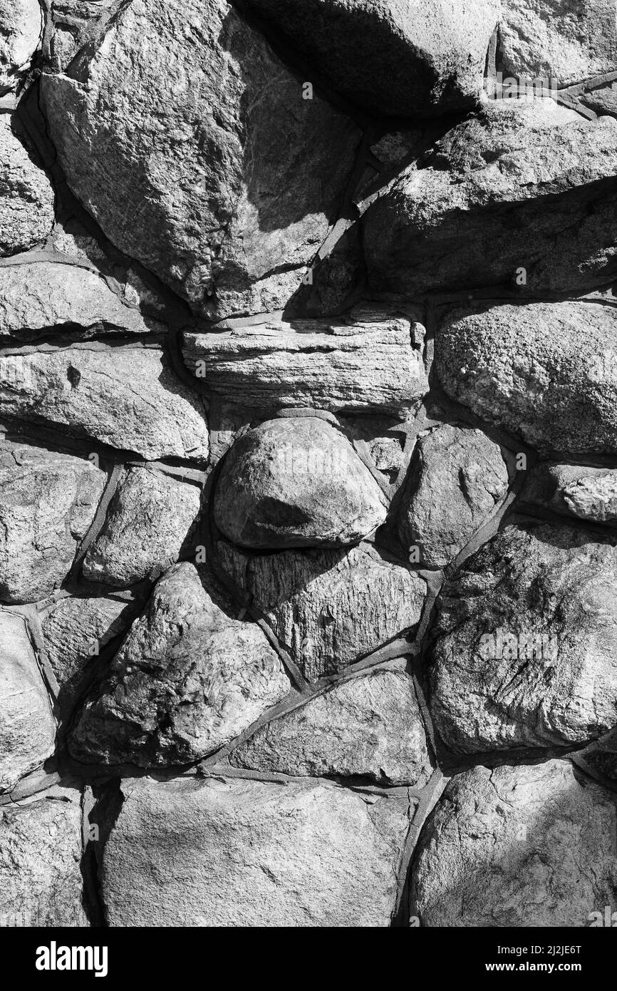 Rustic stone wall built with round boulders and granite stones in black ...