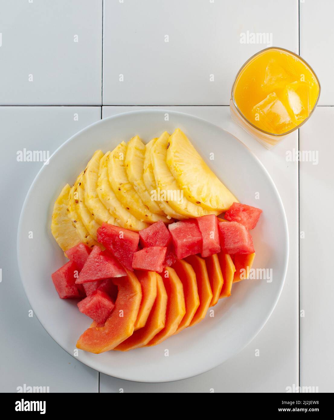 Fruits on a white plate, slices of pineapple papaya and watermelon ...