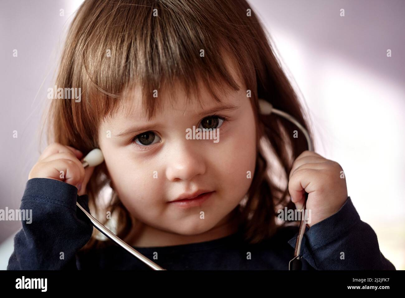 Little girl playing with stethoscope. Close up portrait of cute little ...