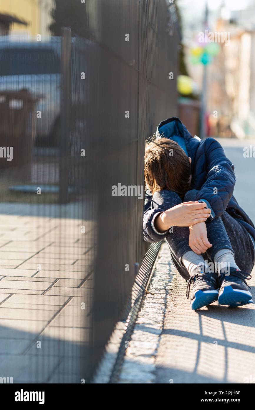 Sad boy sitting and crying on street. Negative emotion Stock Photo - Alamy