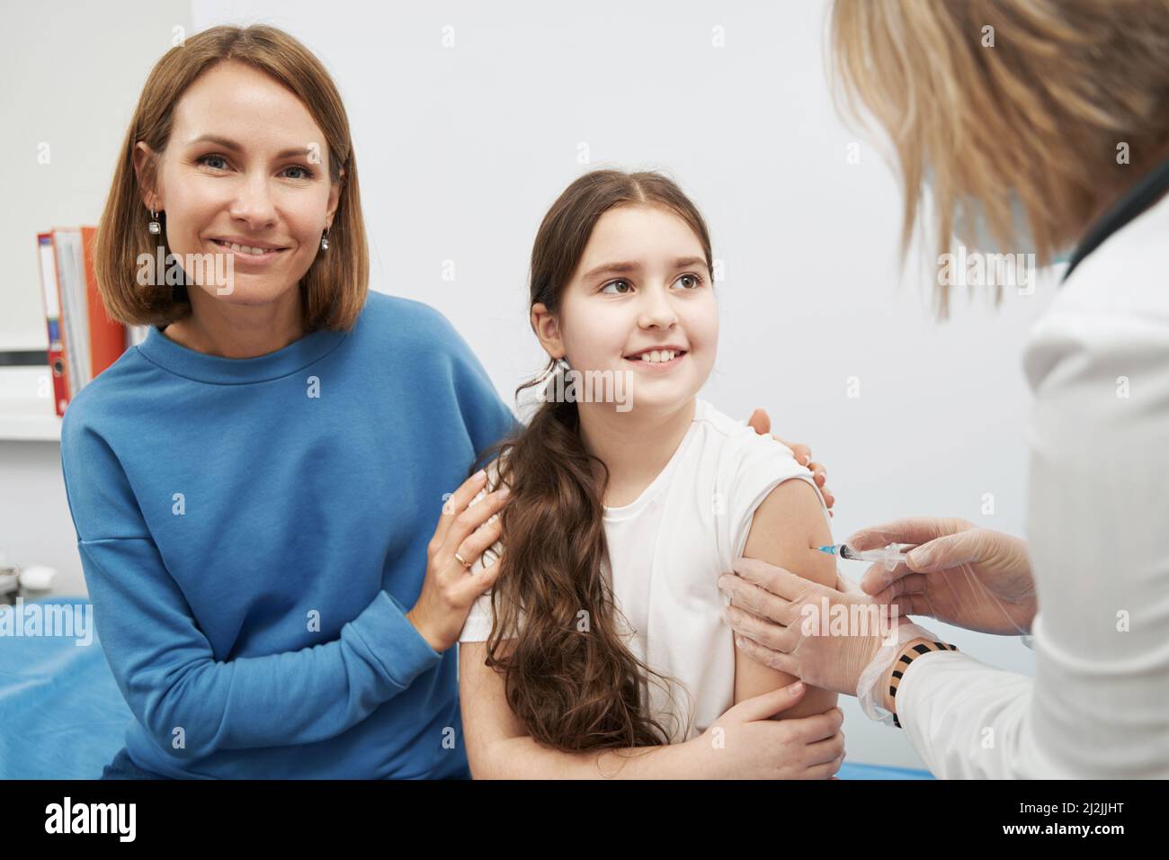 Smiling little girl getting vaccine injection in clinic Stock Photo - Alamy