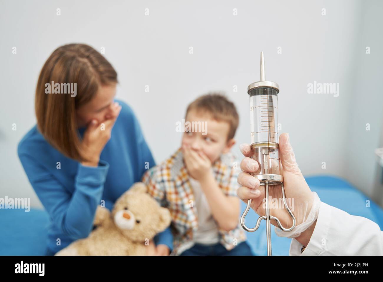 Doctor holding large syringe in front of woman and child Stock Photo ...