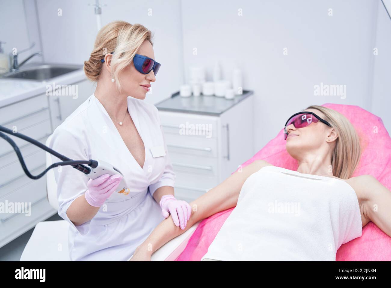 Aesthetic clinic doctor looking at patient before laser therapy session ...
