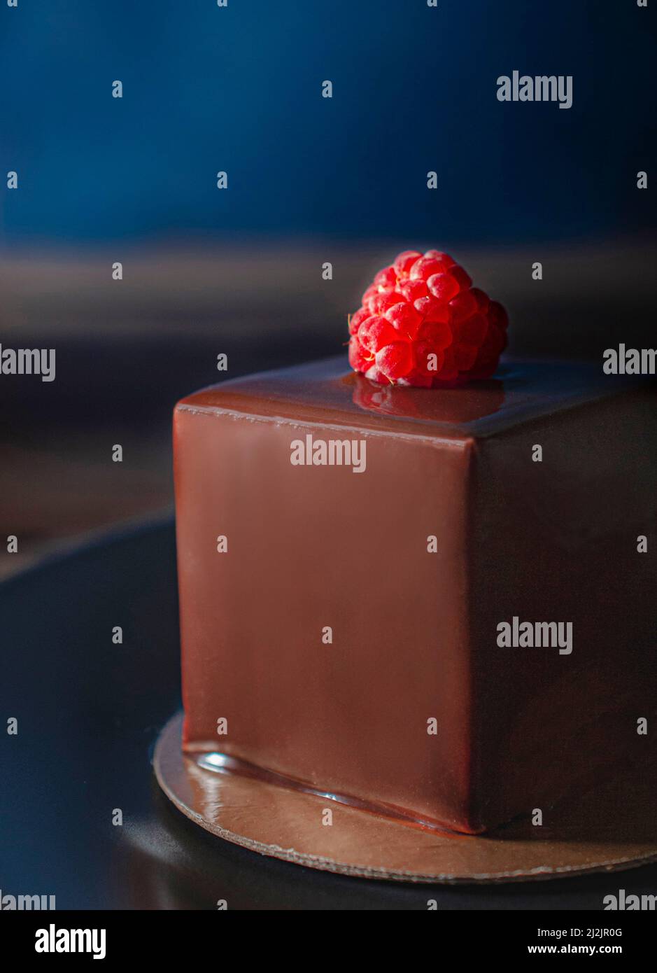 French fine chocolate pastry in the shape of a cube with a raspberry on ...