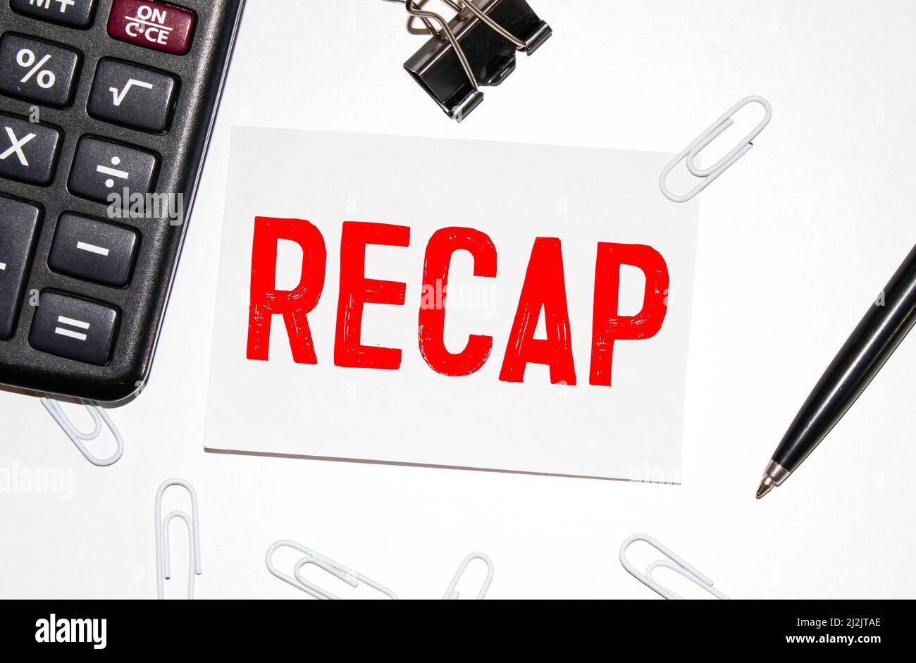RECAP word on white card paper sheet on blue table with white planner ...