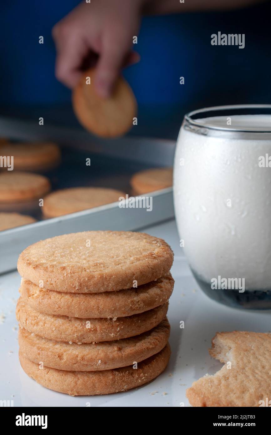 a pile of cookies with a glass of ice milka in a kitchen tray in a dark ...