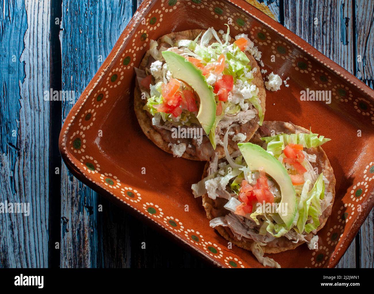 Traditional Mexican food tostadas on a clay or mud plate over a rusic ...