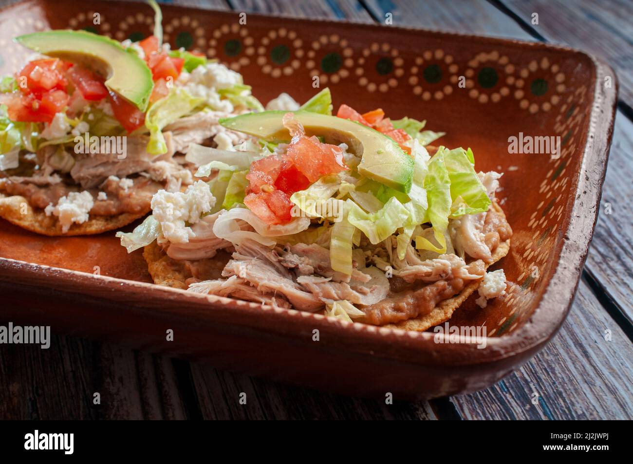 Traditional Mexican food tostadas on a clay or mud plate over a rusic ...