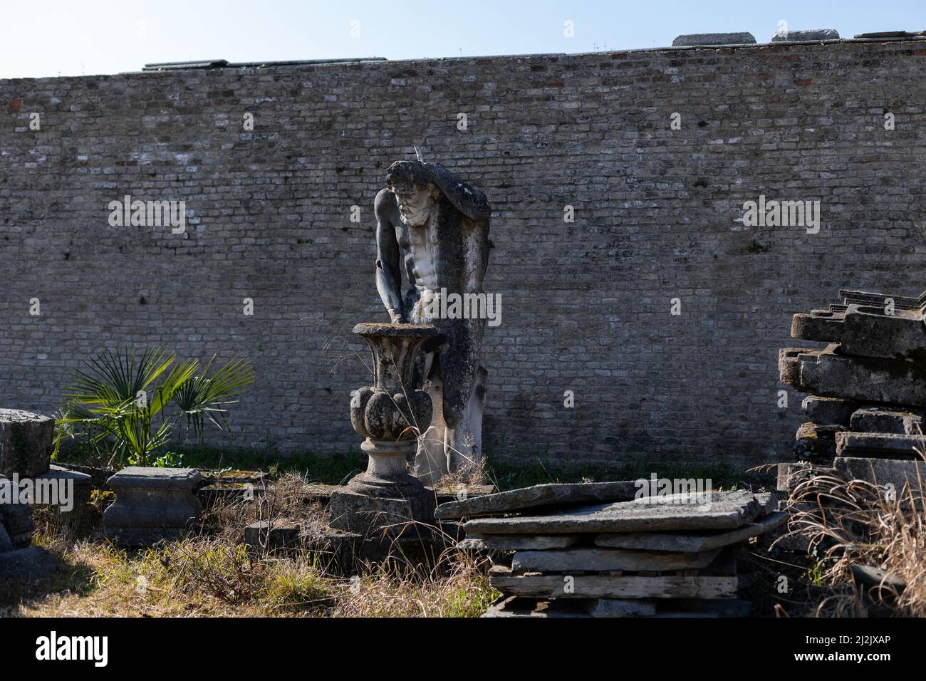 an ancient stone courtyard of a castle with a ruined statue in italy ...