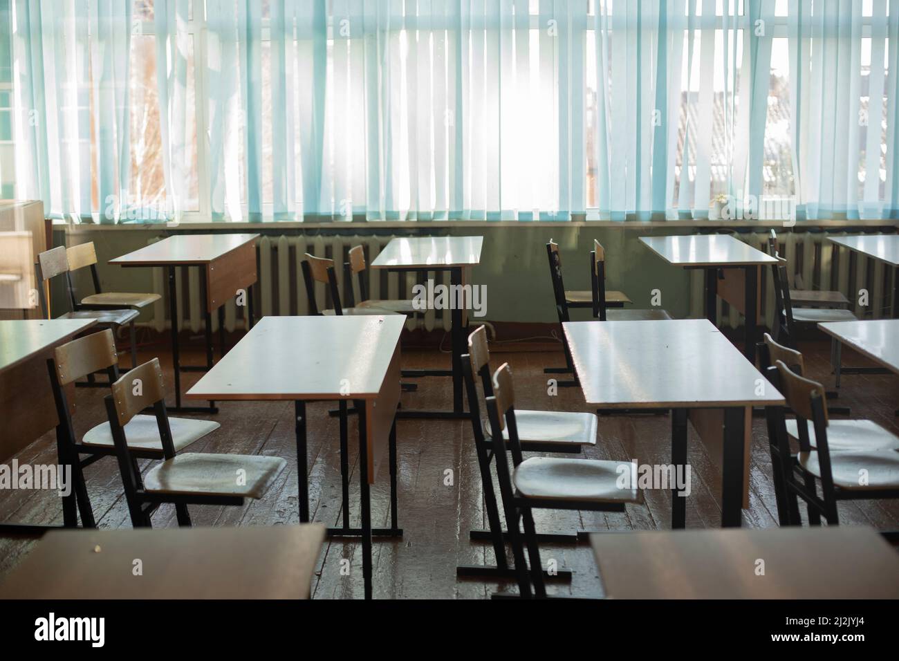Desks for students at school. Classroom is empty. Chairs and tables are ...