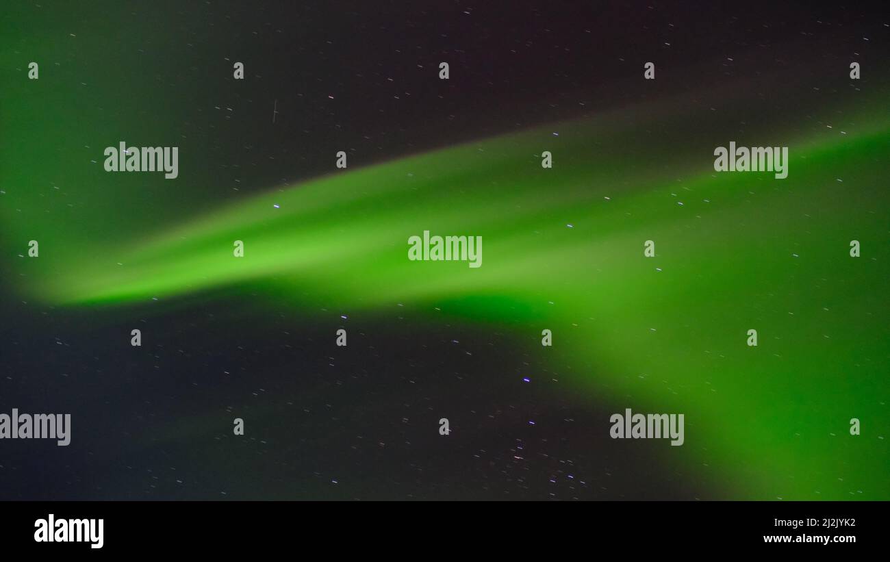 A vertical shot of a bright green band of aurora borealis dancing ...