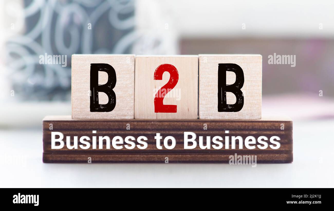 Three wooden cubes with letters B2B on white table, more in background ...