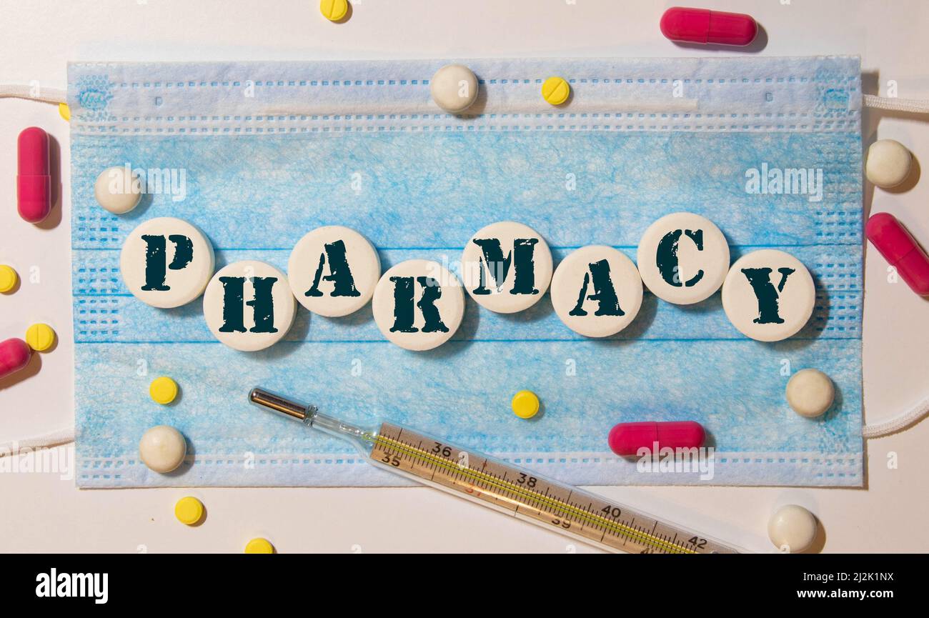 The word 'pharmacy' appearing behind torn blue paper. White pills and ...