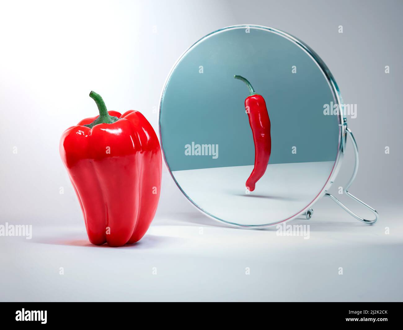Large Red bell pepper in front of a mirror with a reflection of a thin ...