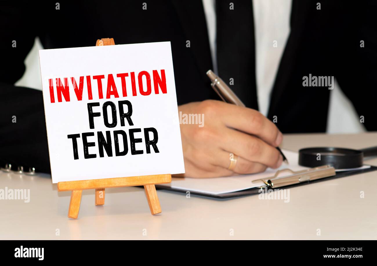 Businessman holding a card with text INVITATION FOR TENDER Keyboard ...