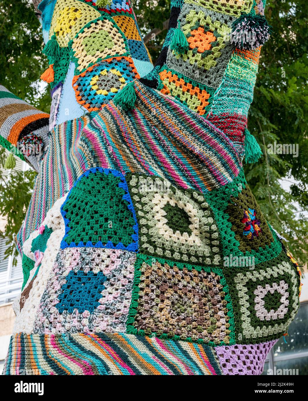Colorful crochet knit on a tree trunk yarn bombing. Patchwork knitted ...